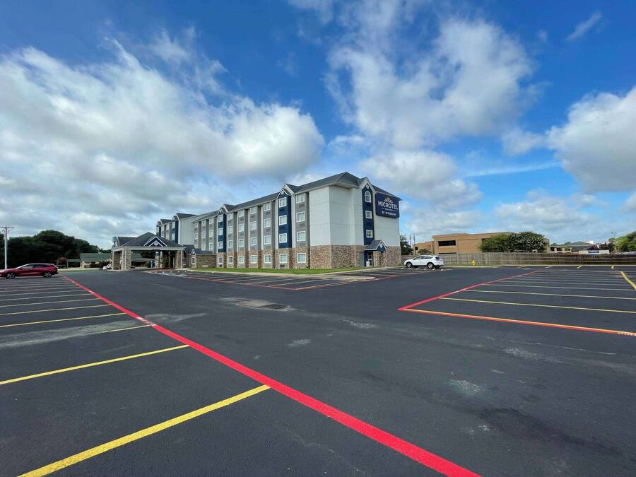 Um Microtel Inn com um estacionamento à frente, com vagas demarcadas e céu claro.
