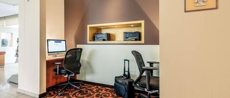 Espaço de negócios com uma mesa, duas cadeiras, uma impressora e um monitor de computador.