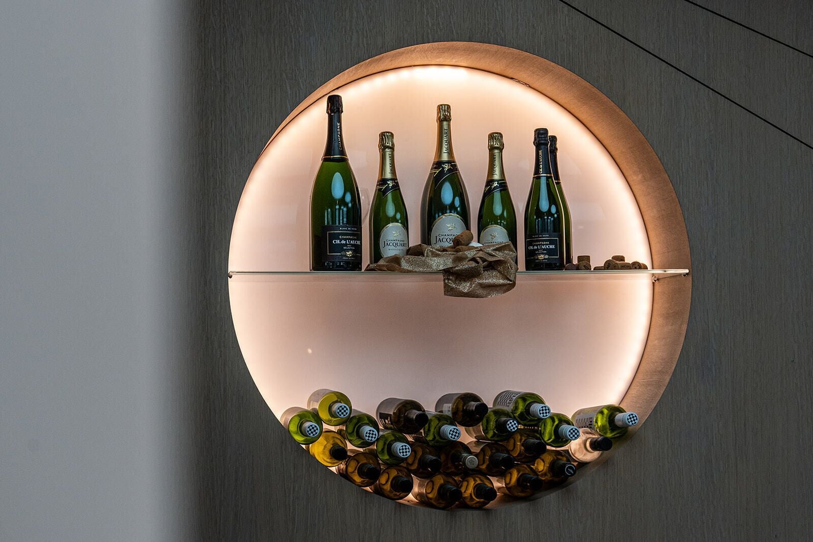 Exposição circular de vinhos, com garrafas e rolhas.