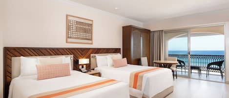 Quarto de hotel com duas camas, varanda com vista para o mar e uma janela ampla.