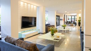 Uma sala de estar moderna com televisão de tela plana, assentos confortáveis, uma mesa de centro e um espaço de jantar com cadeiras e uma mesa.