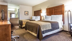 Quarto de hotel com duas camas, uma escrivaninha e uma cadeira.