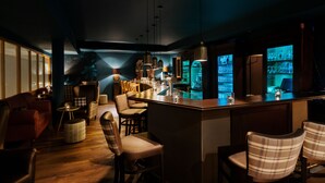 Uma área de bar com mobiliário de madeira, balcão e prateleiras com copos.