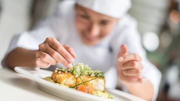 Um chef preparando um prato com um pires e uniforme brancos.