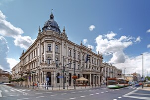 Um edifício histórico com uma cúpula imponente e a inscrição 'Grand Hotel' em sua fachada.