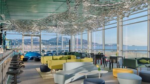 Uma área de estar moderna com vista para o mar, oferecendo diversas opções de assento e um design de teto exclusivo.