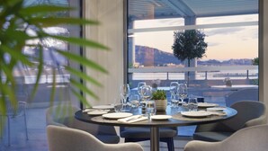 Mesa de jantar posta com pratos, copos e talheres, com vista panorâmica.