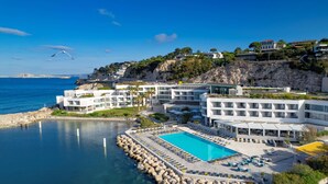 Um resort com uma grande piscina, vários edifícios e vista para o mar.