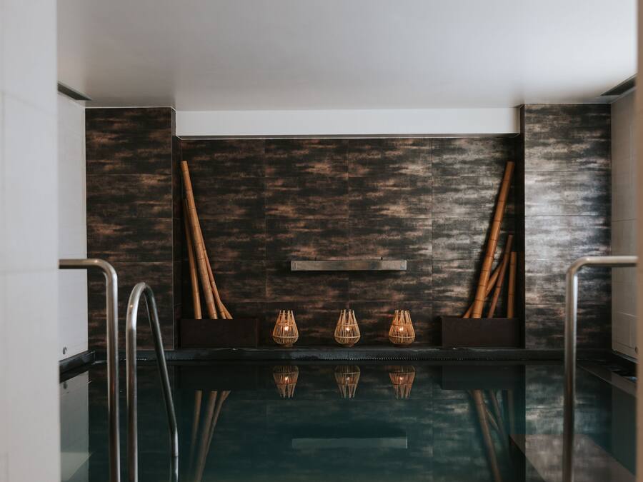 Piscina interior moderna com parede de madeira escura e grades de metal.