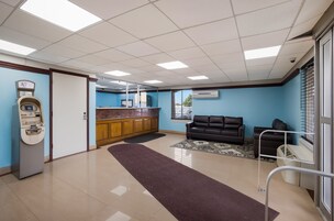 Um lobby limpo e bem iluminado com balcão de recepção, caixa eletrônico, sofá e uma grande janela.