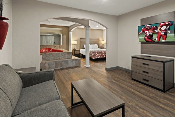Quarto de hotel com sofá, televisão, escrivaninha e cama.