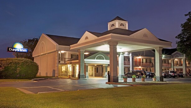Um hotel Days Inn com área de estacionamento coberta, vários quartos de hóspedes e uma entrada bem iluminada.