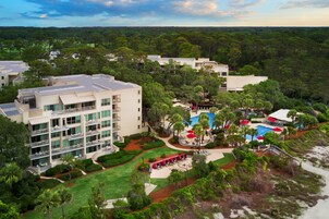 Vista aérea de um resort com vários edifícios, piscina e áreas ajardinadas.