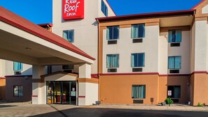Um Red Roof Inn com um edifício de dois andares, entrada coberta e estacionamento.