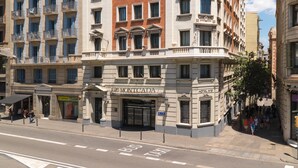 Um hotel de vários andares com uma fachada em tijolos vermelhos marcante, janelas amplas e um design arquitetônico clássico.