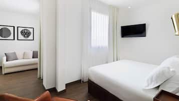 Quarto de hotel com cama, sofá, televisão e obras de arte na parede.