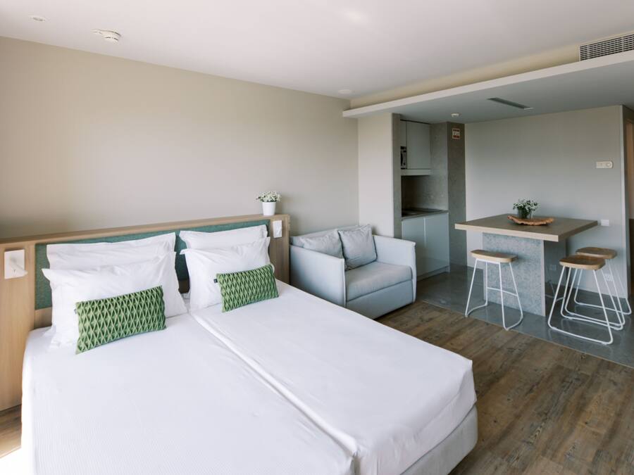 Quarto de hotel com duas camas, uma cozinha compacta e uma área de estar.