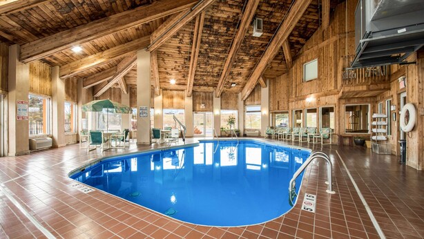 Piscina interna com teto de madeira e chão de azulejos.