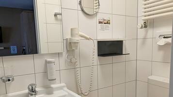 Um banheiro com pia, espelho, porta-toalhas, vaso sanitário e um banquinho pequeno.