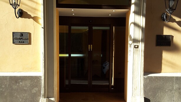 Entrada de hotel com porta de vidro, placa indicando 