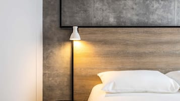 Uma cama com almofadas brancas e uma mesa de cabeceira com abajur.
