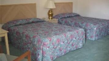 Quarto com duas camas, uma mesa de cabeceira com abajur e uma pequena mesa.