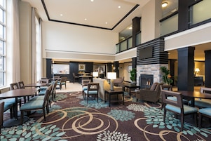 Um hall de hotel com área de refeições, assentos e lareira.