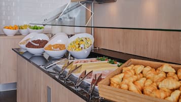 Buffet com diversas opções de comida, incluindo frutas, cereais e doces.
