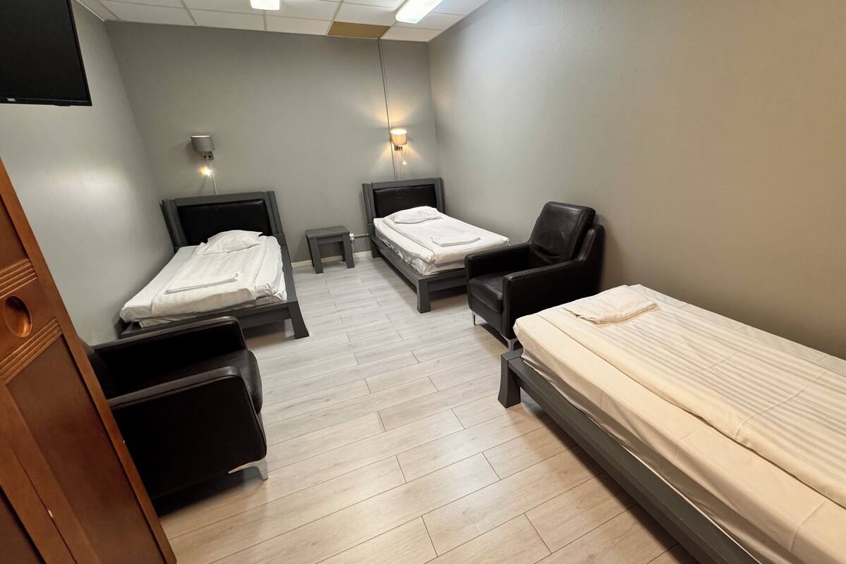 Quarto de hotel com duas camas de solteiro, uma escrivaninha, uma cadeira e uma pequena mesa.