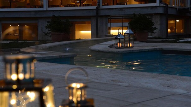 Um hotel com piscina, área de estar externa e entrada bem iluminada.