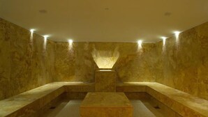 Uma sala de spa com área de estar central, bancos e mesa para massagem.