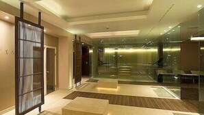 Um hall de hotel moderno com divisória de vidro, balcão de recepção e área de estar.