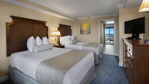 Quarto de hotel com duas camas, televisão, penteadeira e um quadro na parede.
