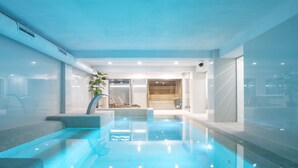 Piscina interior moderna com água cristalina, emoldurada por um design minimalista e iluminação embutida.