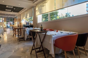 Restaurante com mesas preparadas para refeições, vista para o exterior e design de interiores moderno.