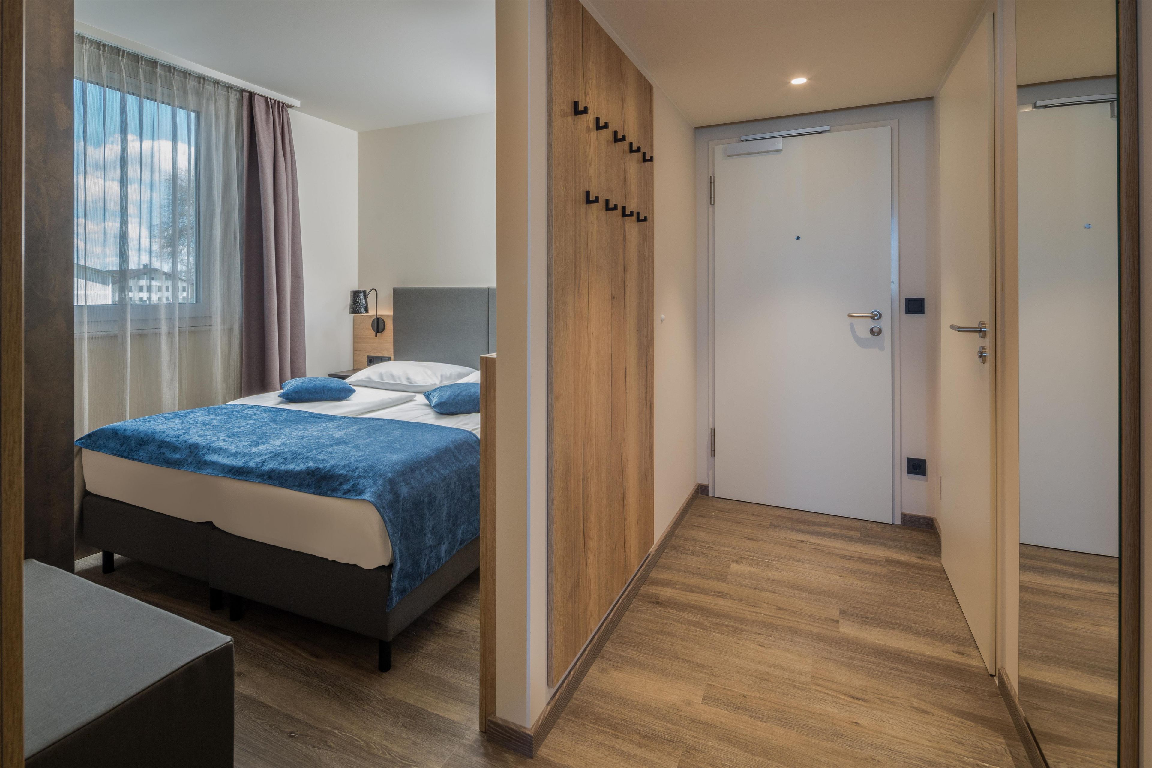 Quarto de hotel moderno com cama, escrivaninha, guarda-roupa e porta.