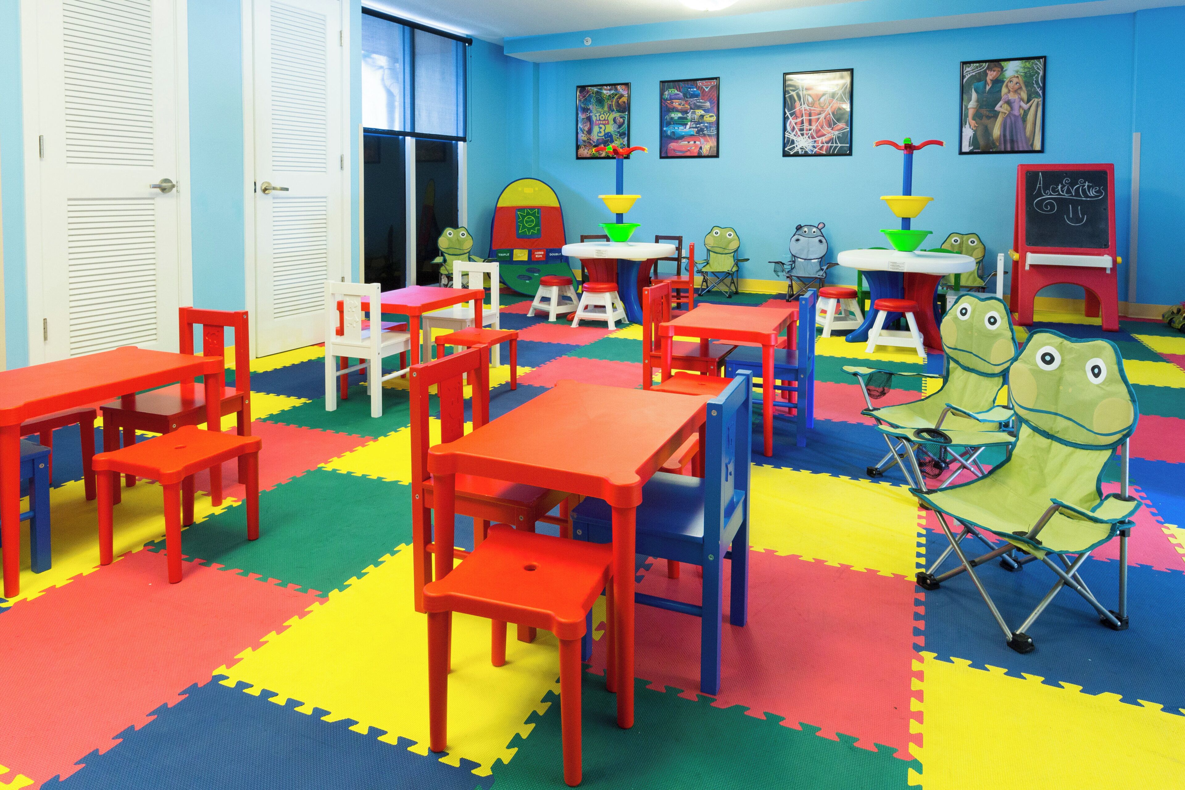 Uma sala de jogos infantil com mobiliário colorido e cartazes educativos nas paredes.