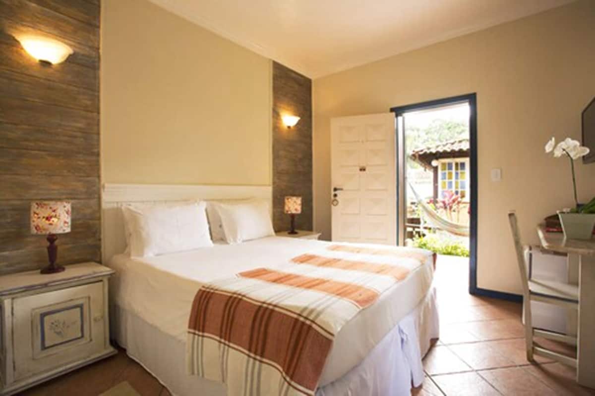 Quarto com cama, abajures, uma porta e vista para o exterior.
