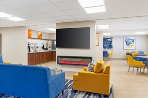 Uma área de estar moderna com televisão de tela plana, lareira e sala de jantar com cadeiras amarelas.