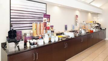 Um buffet de café da manhã com diversos alimentos e um espaço para café.