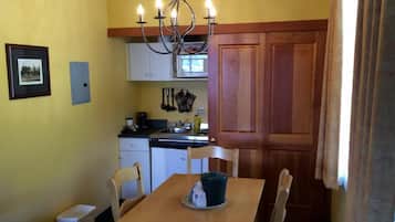 Cozinha compacta com mesa de jantar, cadeiras, lustre e porta de madeira.