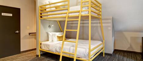 Uma cama beliche com escada, uma mesinha de cabeceira e um abajur.