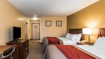 Quarto de hotel com duas camas, uma escrivaninha com televisão, uma porta e um quadro fixado na parede.