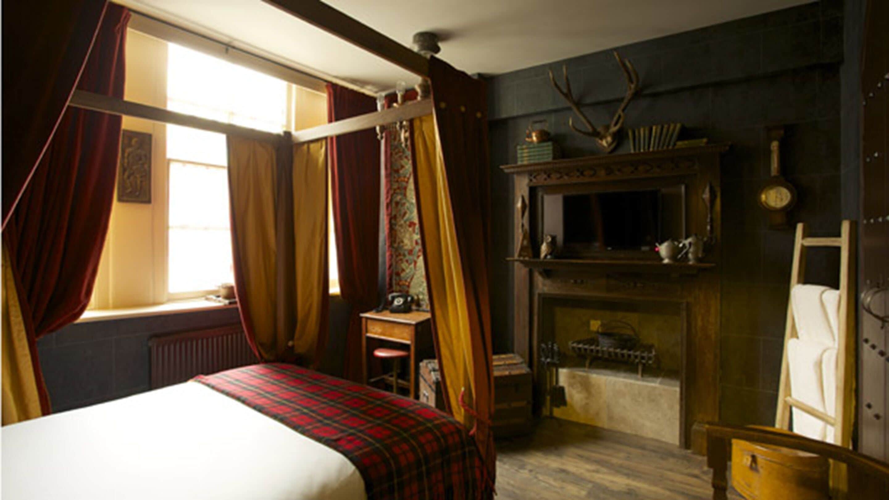 Quarto tradicional com cama, lareira e janela com cortinas.
