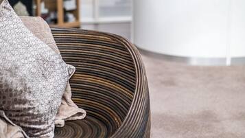 Decoração moderna com um sofá redondo de vime, uma recepção com balcão branco e uma grande janela.