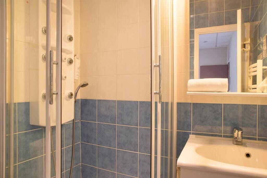 Casa de banho com cabine de chuveiro em vidro, lavatório e espelho.