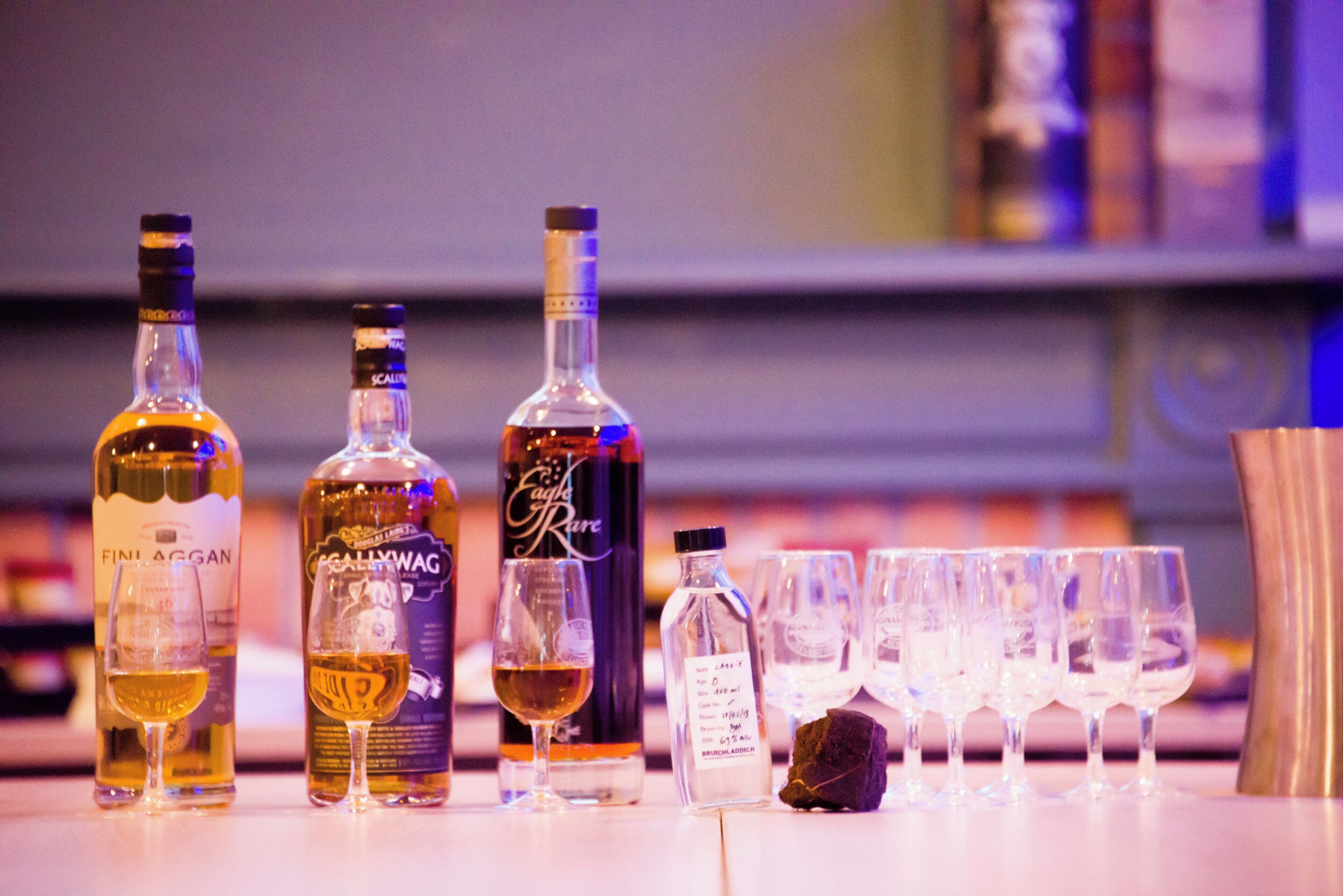 Ambiente de bar com garrafas de bebidas alcoólicas e copos.