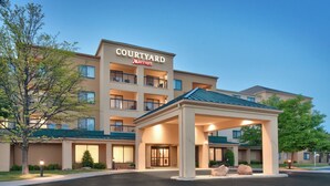 Um hotel Courtyard Marriott com entrada coberta, várias varandas e fachada bem iluminada.