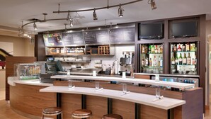 Uma área de bar moderna com um balcão comprido, banquetes e um quadro de menu.