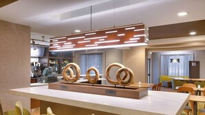 Uma área de bar moderna com um balcão comprido, vários bancos e uma luminária de teto diferenciada.